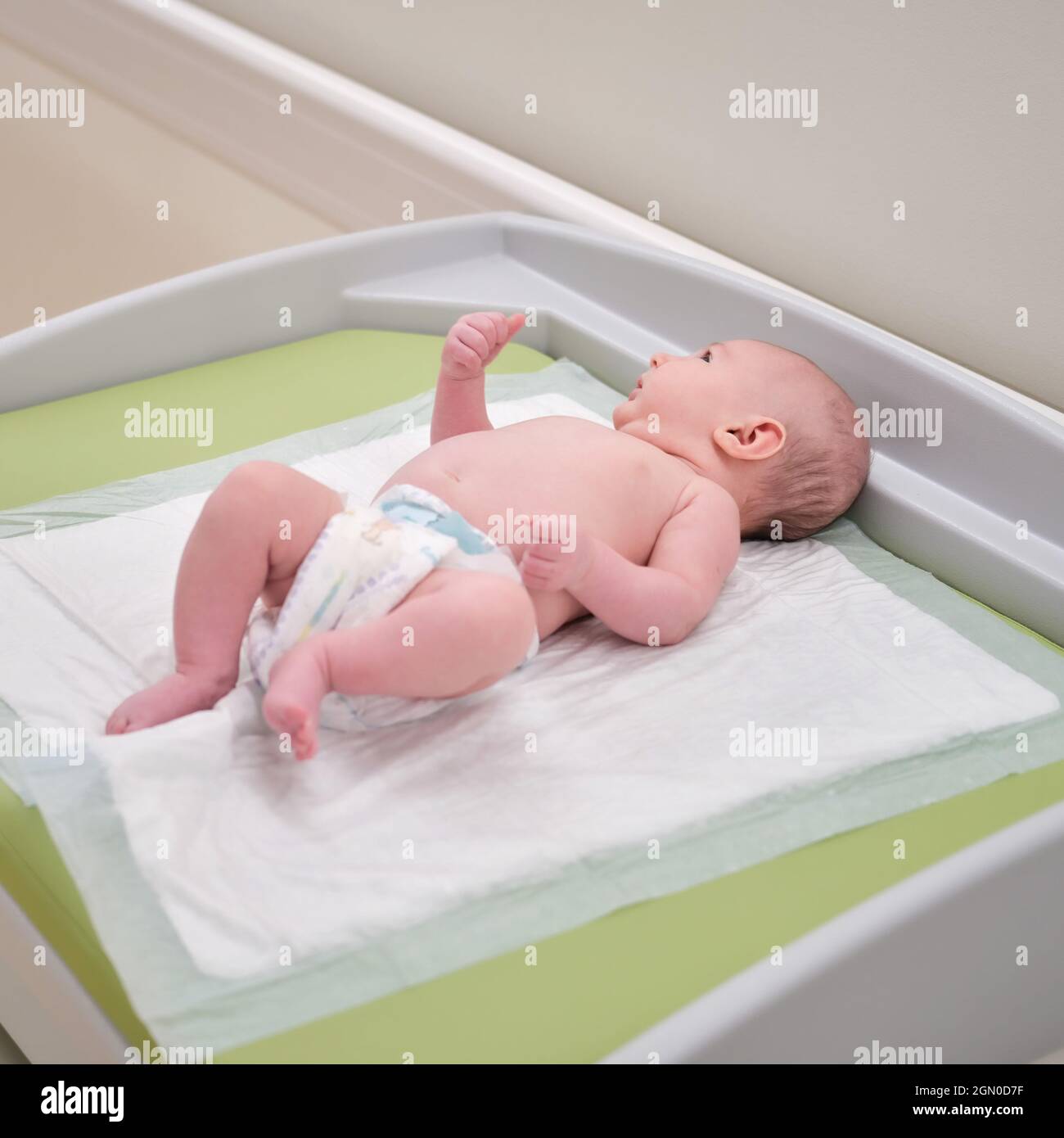 The baby infant boy lies in a diaper on the changing table in the ...
