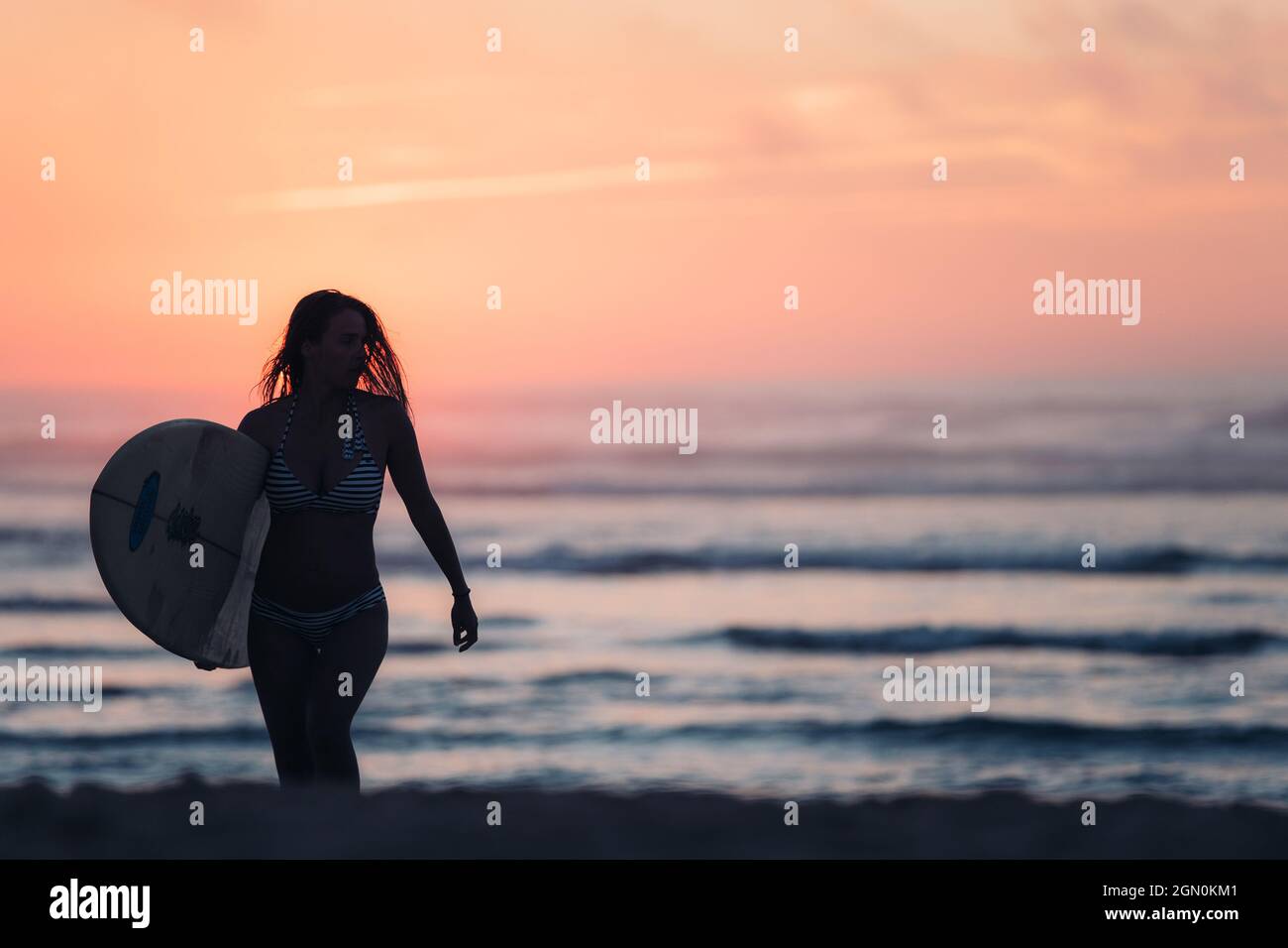 Female surfer goes with surfboard on the beach in sunset, surfing ...