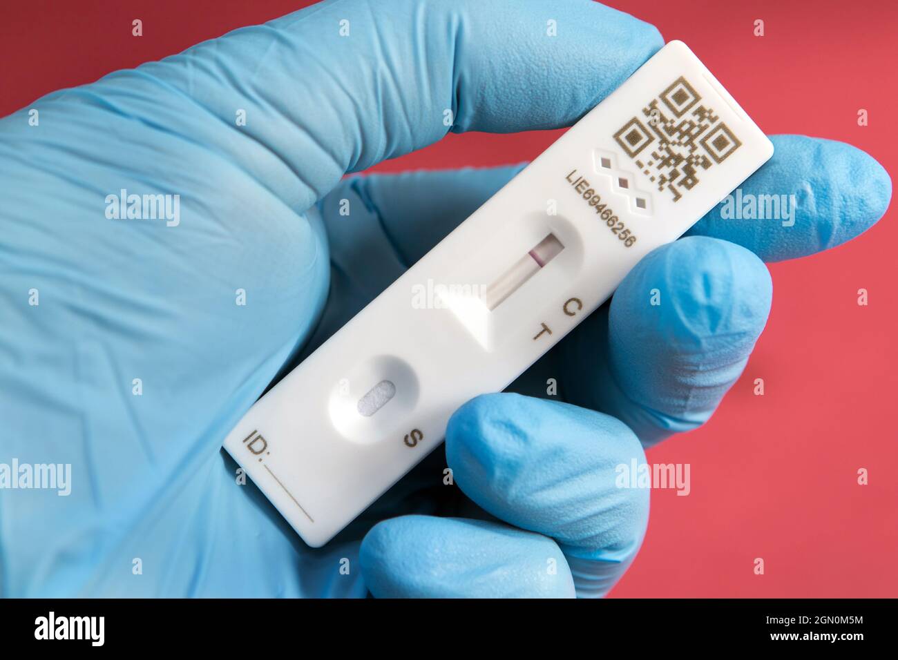 Blue medical gloves holding a Covid 19 negative result lateral flow ...