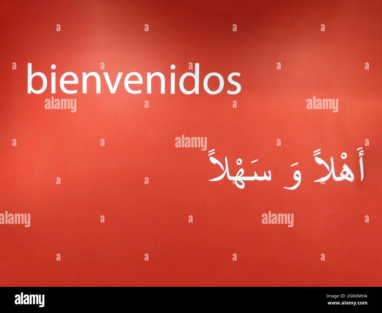 Poster with the word welcome in Spanish and Arabic with red background ...