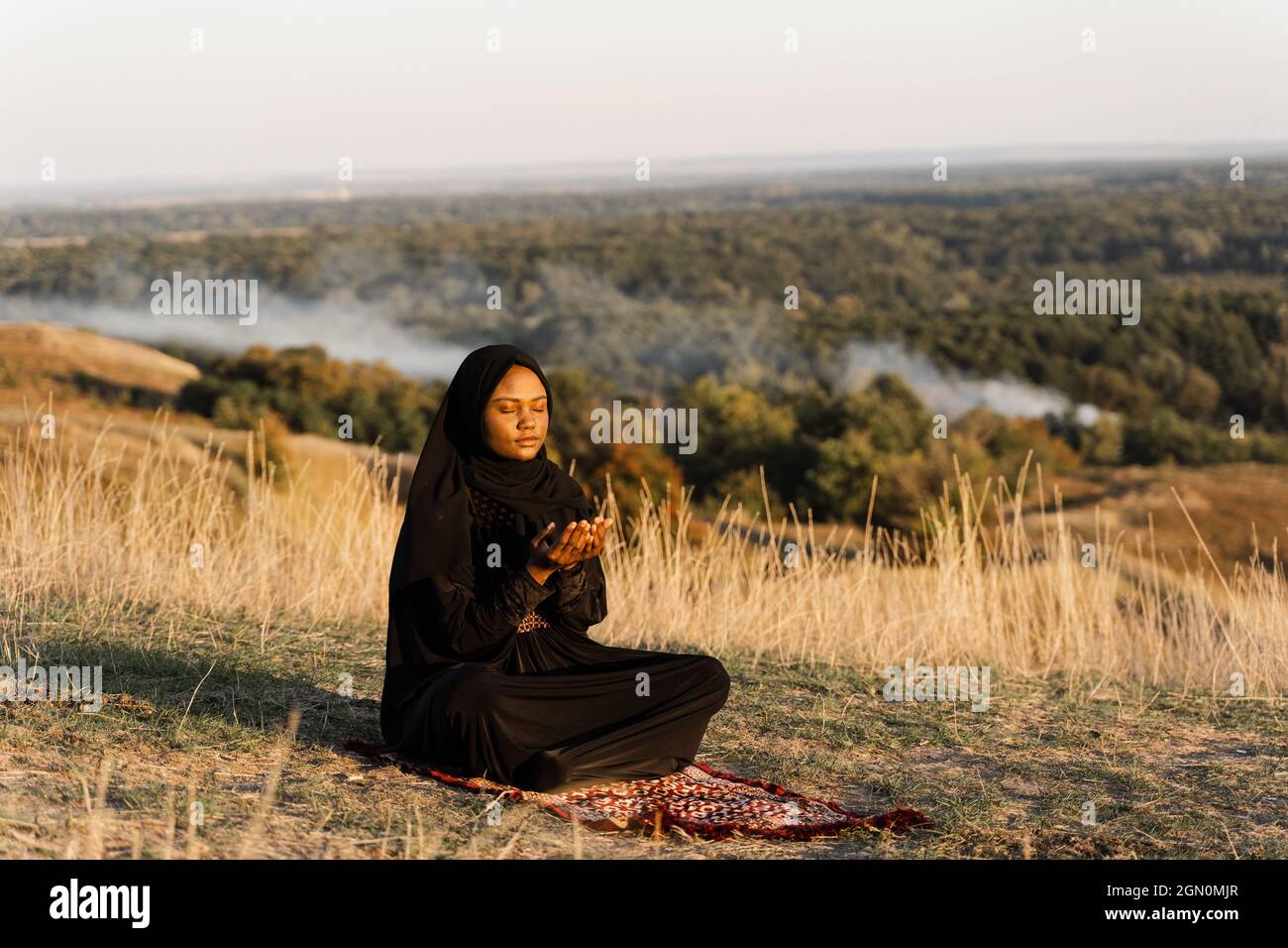 Black muslim woman praying on the carpet. Solat praying on the ...
