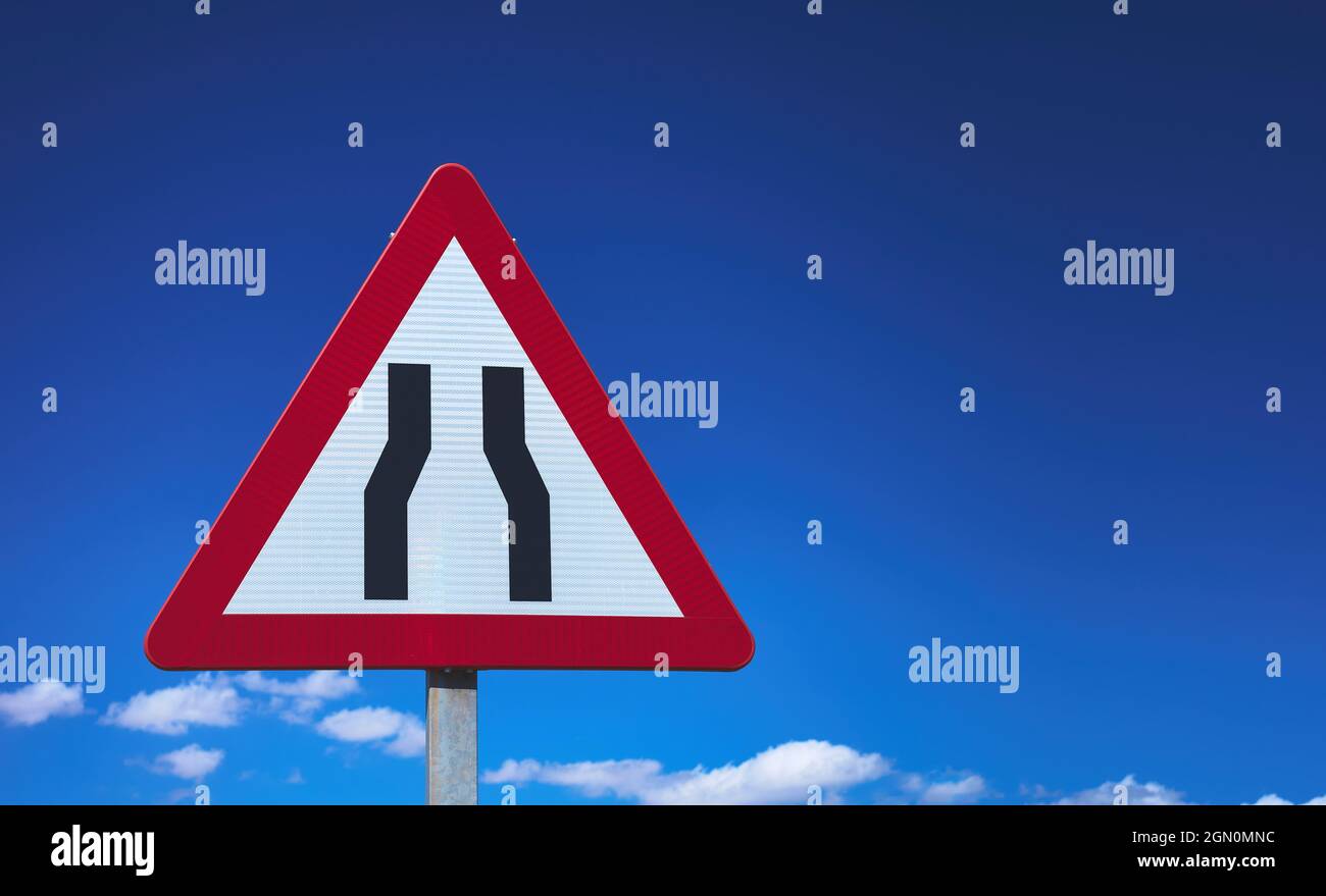 detail of a narrowing traffic sign over a blue cloudy sky Stock Photo ...