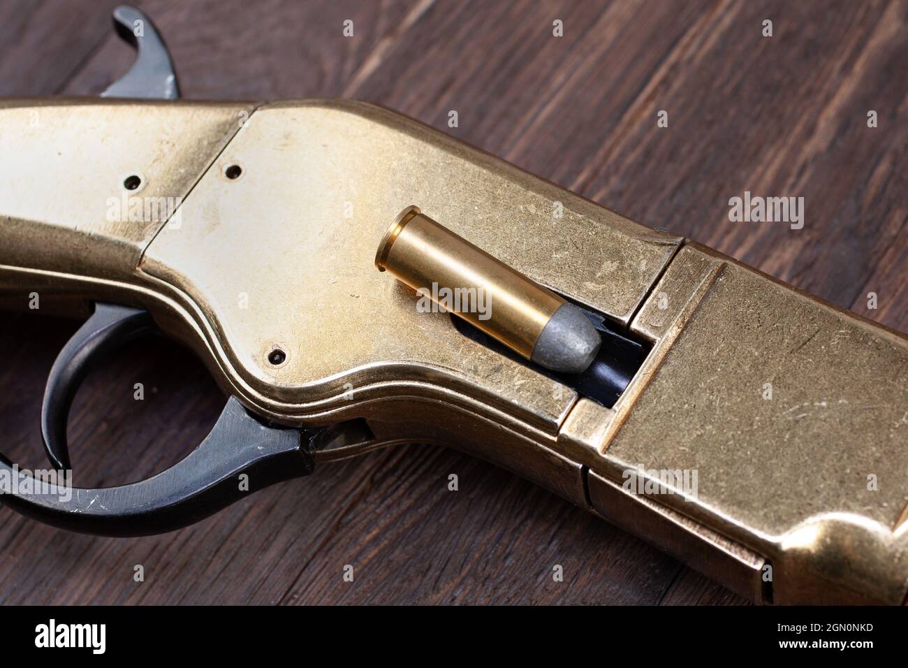 Old west gun - lever-action repeating rifle with bullet on wooden table ...