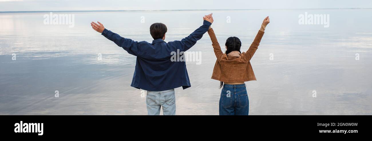 Back view of couple holding hands near sea, banner Stock Photo - Alamy
