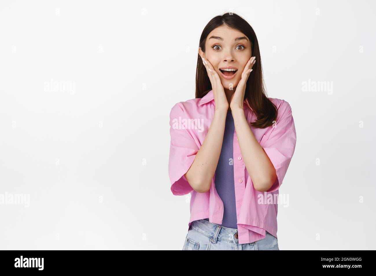 Portrait of cute girl gasp and look surprised, saying wow, looking with ...