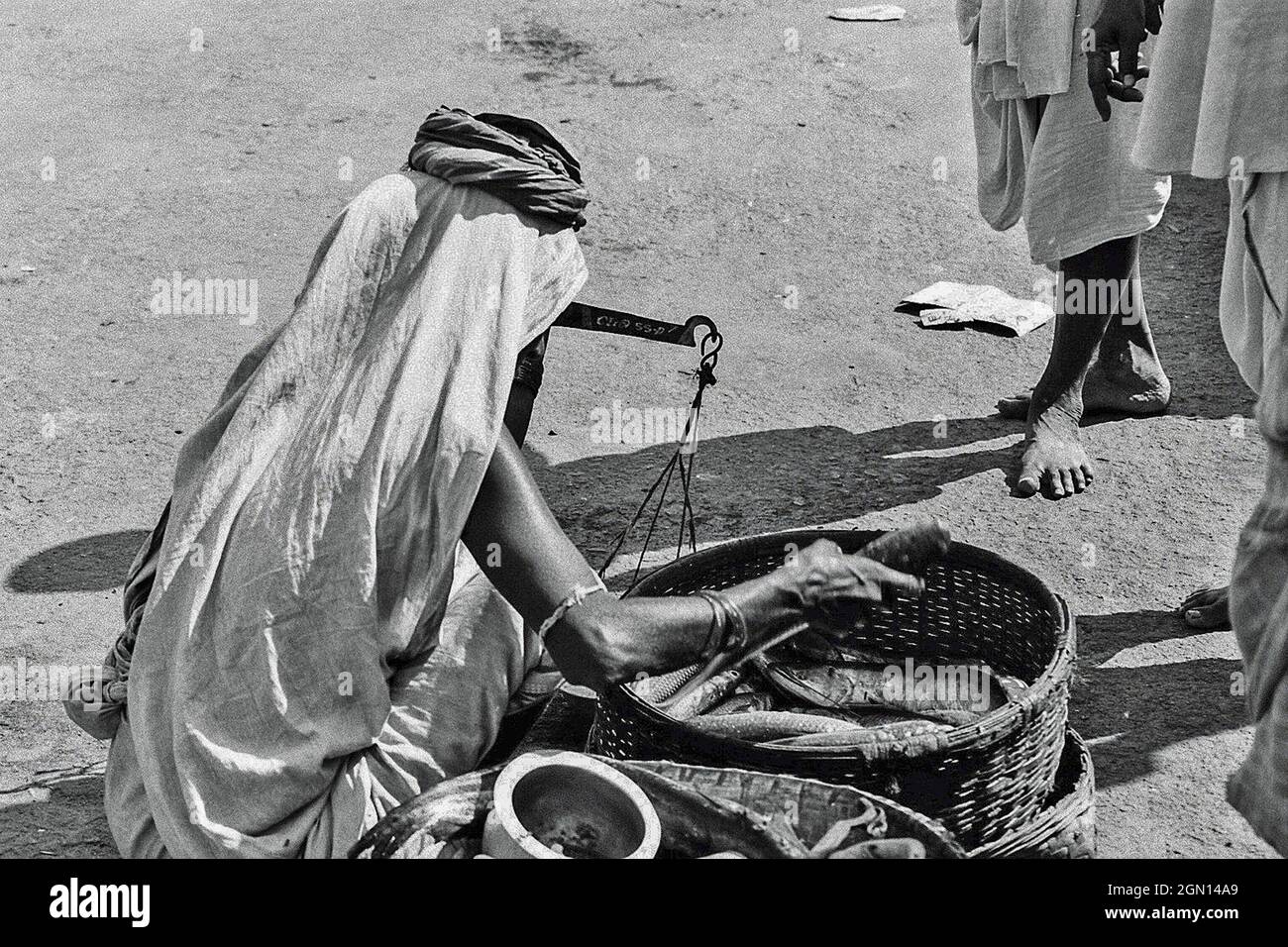 Near view of a street merchant with a scale and a basket with fishes ...