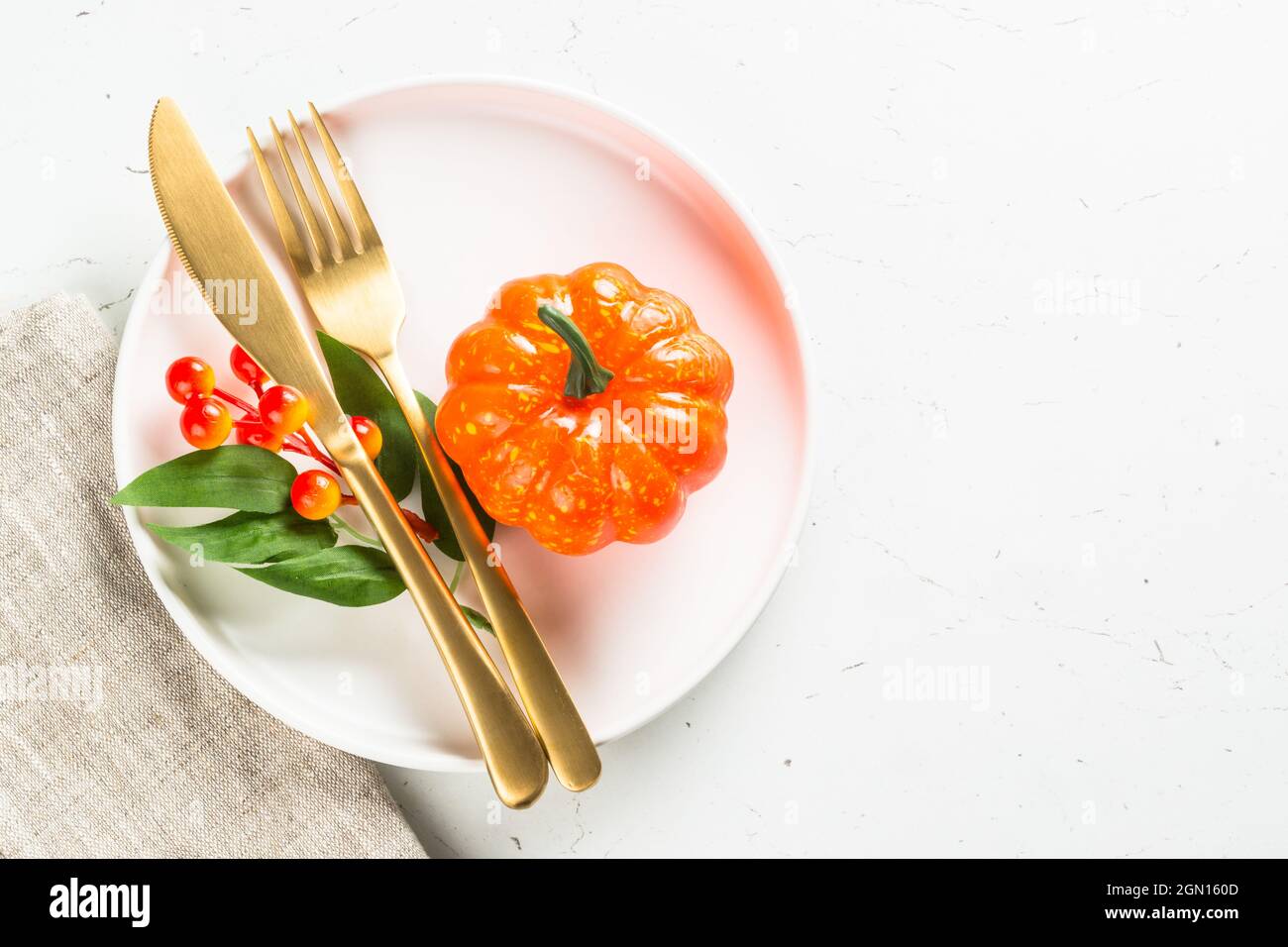Autumn table setting with white plate, golden cutlery and fall ...