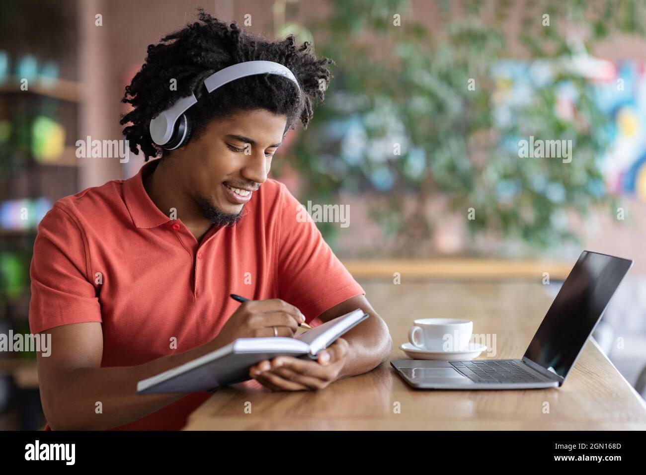 Young Black Guy Taking Notes While Studying Online With Laptop In Cafe ...