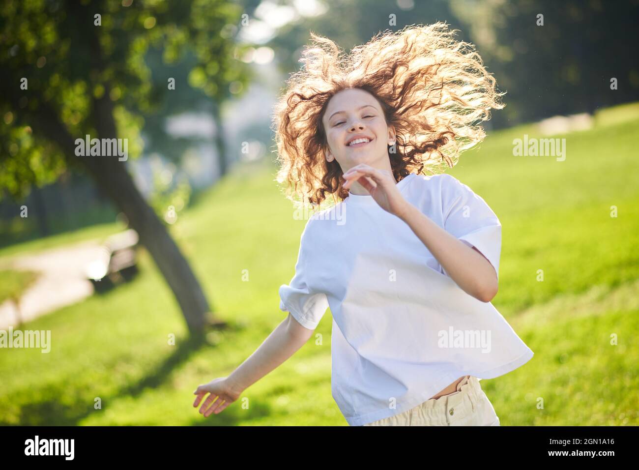A ginger long-haired girl running in a park and looking happy Stock ...