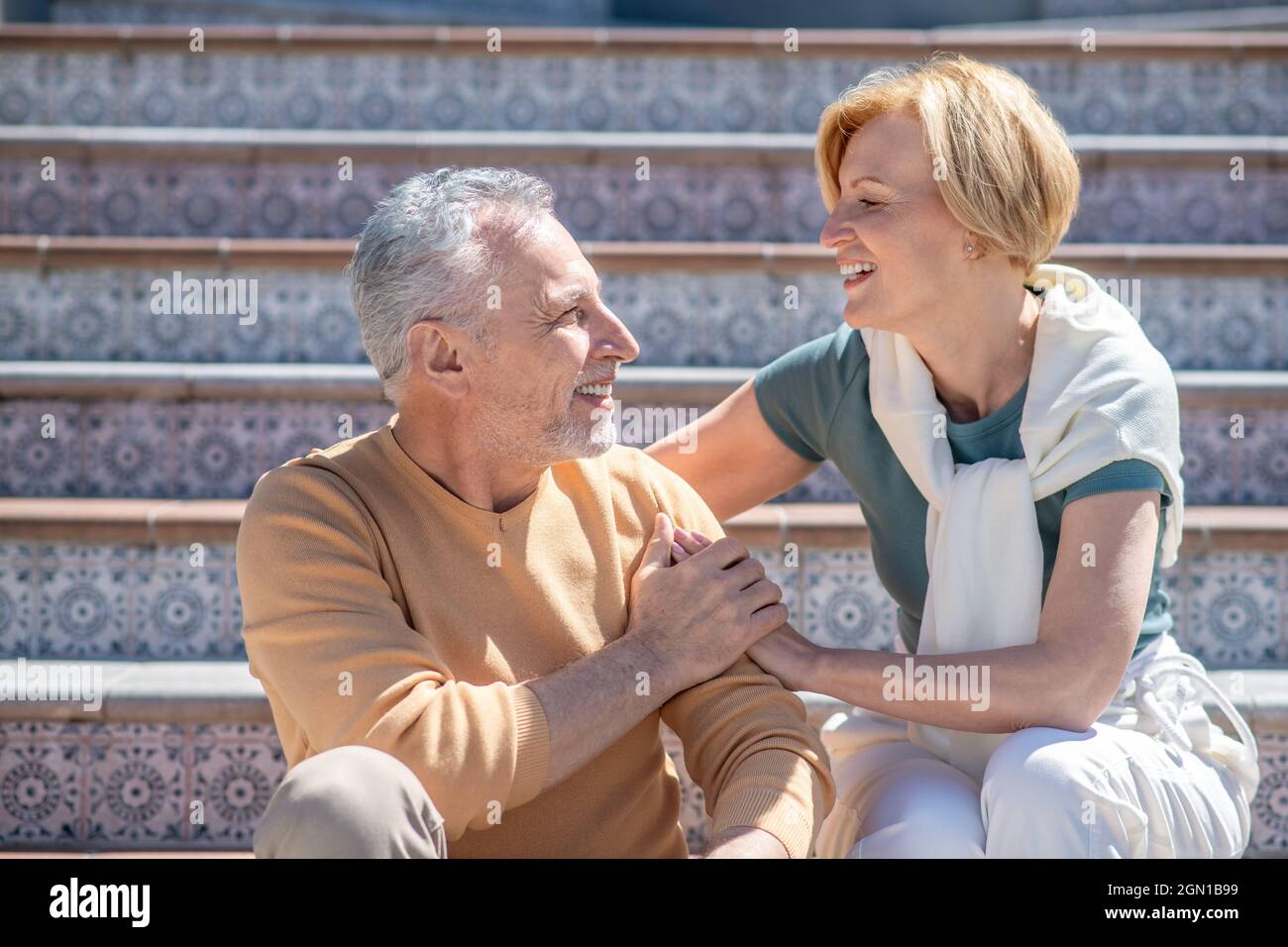 Happy middle-aged couple seated on the steps Stock Photo - Alamy