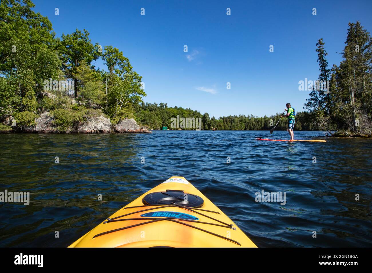 Tip of a yellow kayak and man on SUP stand-up paddleboard on Indian ...
