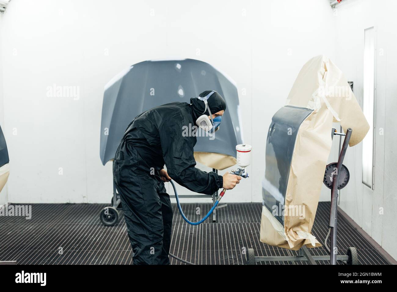 man in protective suit spray paints hood of auto parts Stock Photo - Alamy