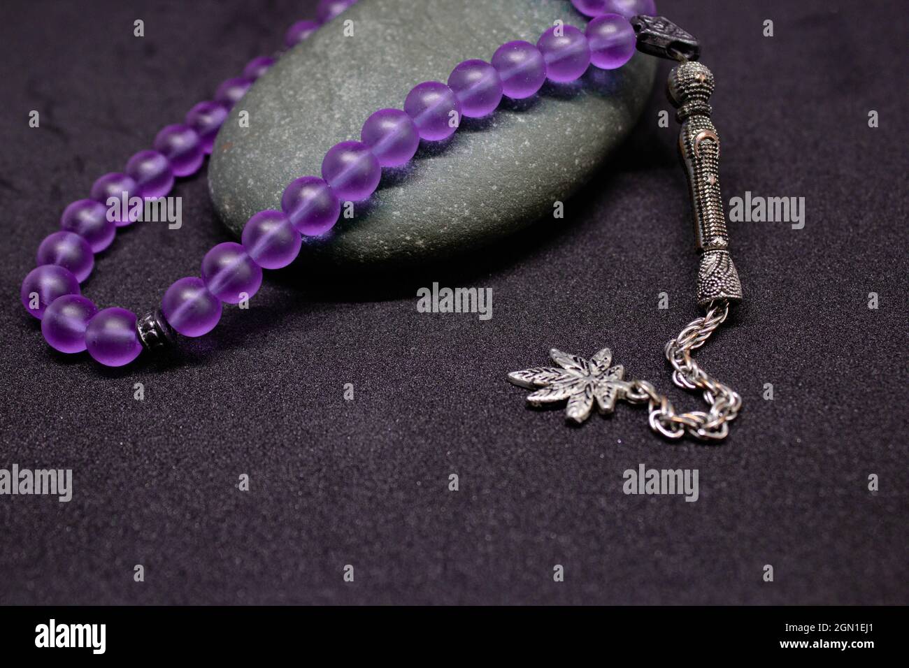 Purple prayers bead(rosary) with a silver marihuana sign. An islamic ...