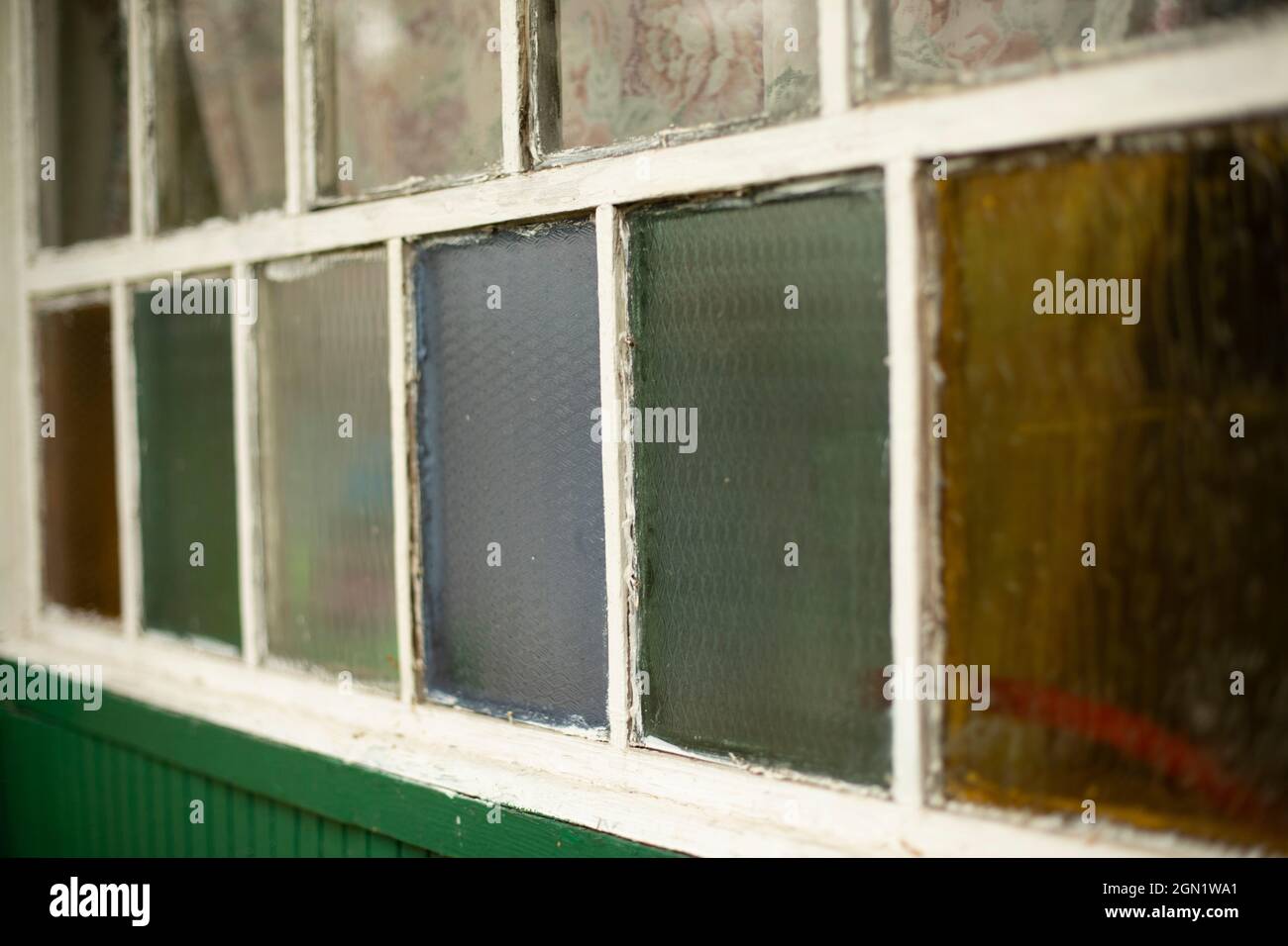 An old window in the village. Colored glass in the window frame. Facade ...