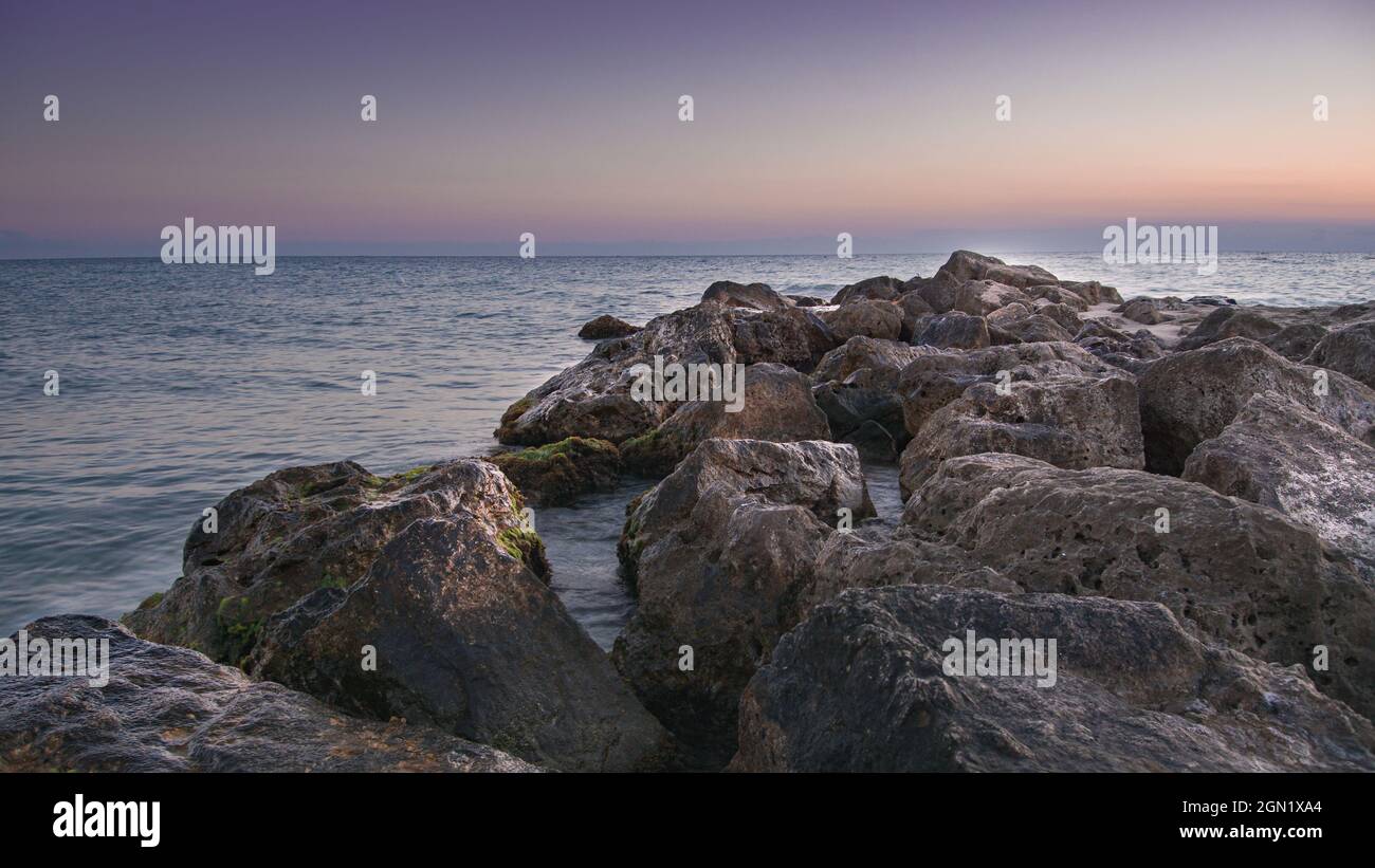 Beautiful horizon of the sea and the rocks on the beach on a sunset ...