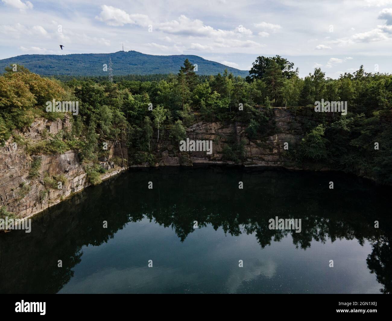Deep lake surrounded by a cliff and dense fore Stock Photo - Alamy