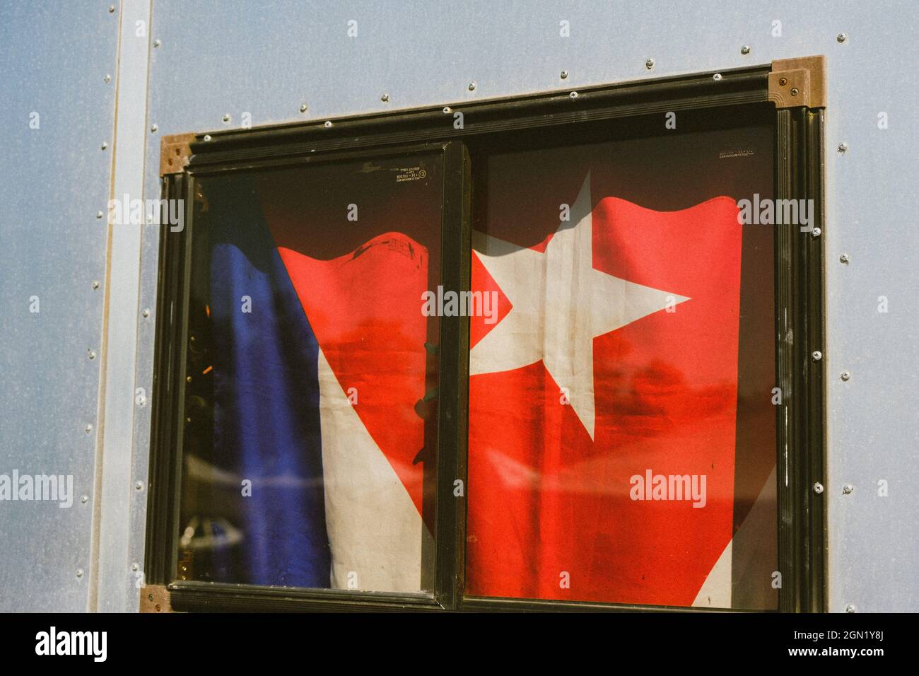 Closeup of a window with the flag of Cuba covering it from the inside ...