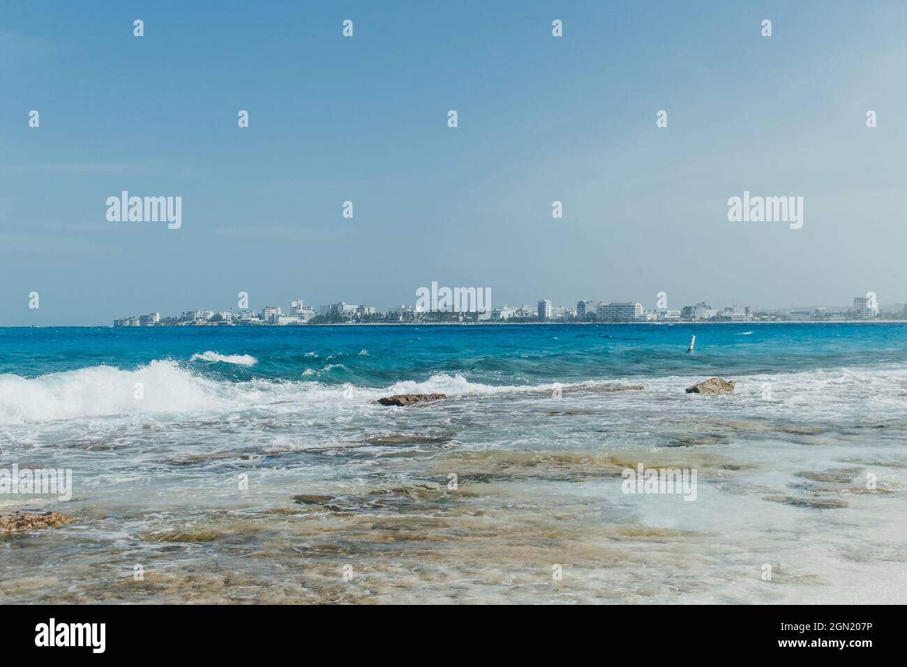 Beautiful view of the wavy sea hitting the rocky beach gleaming under ...