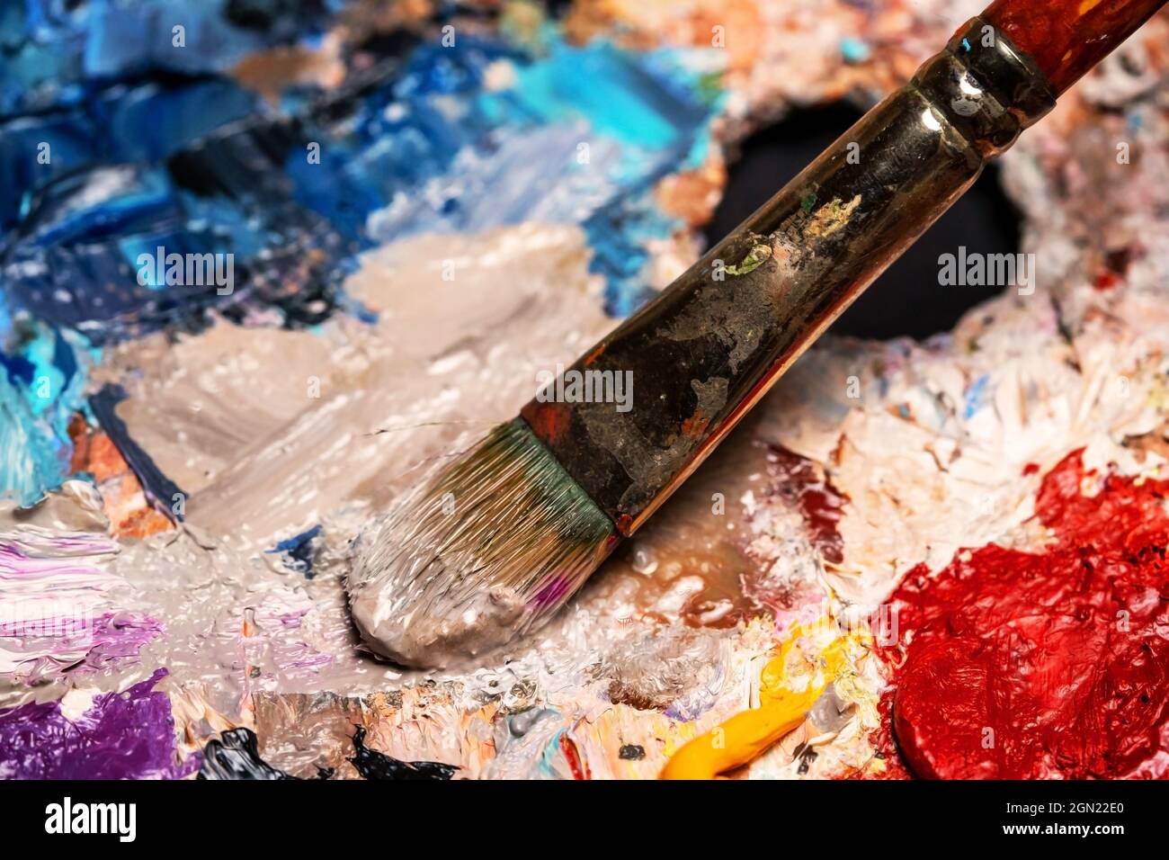 Brush mixing bright colors from relief layers of oil paints Stock Photo ...