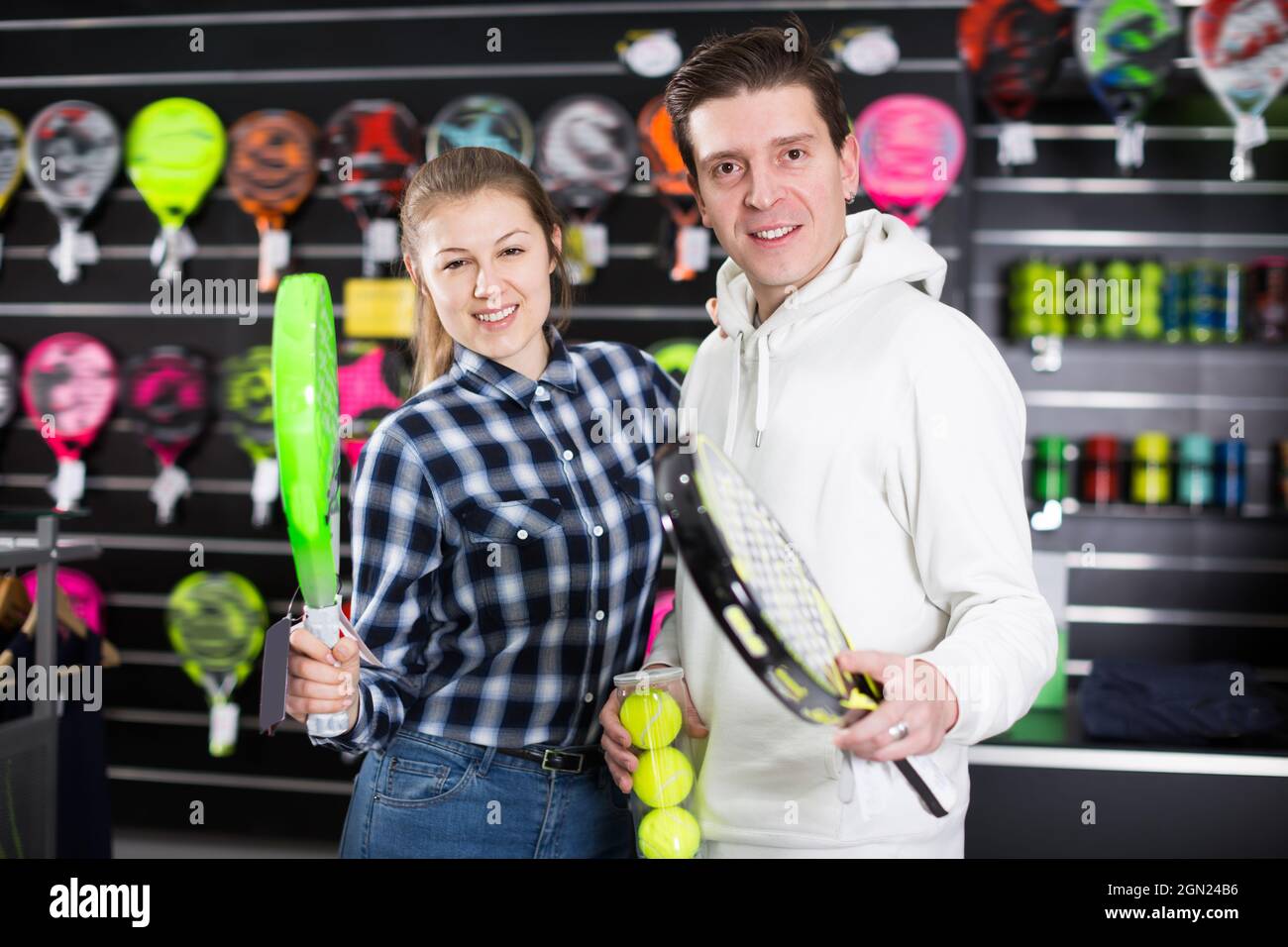 Glad couple choosing padel racket and balls Stock Photo - Alamy
