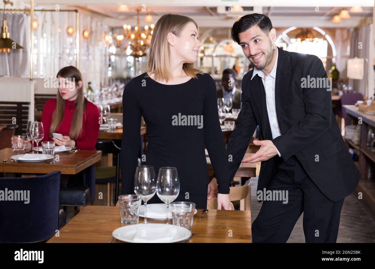 Gentleman helping woman with her chair in restaurant Stock Photo - Alamy