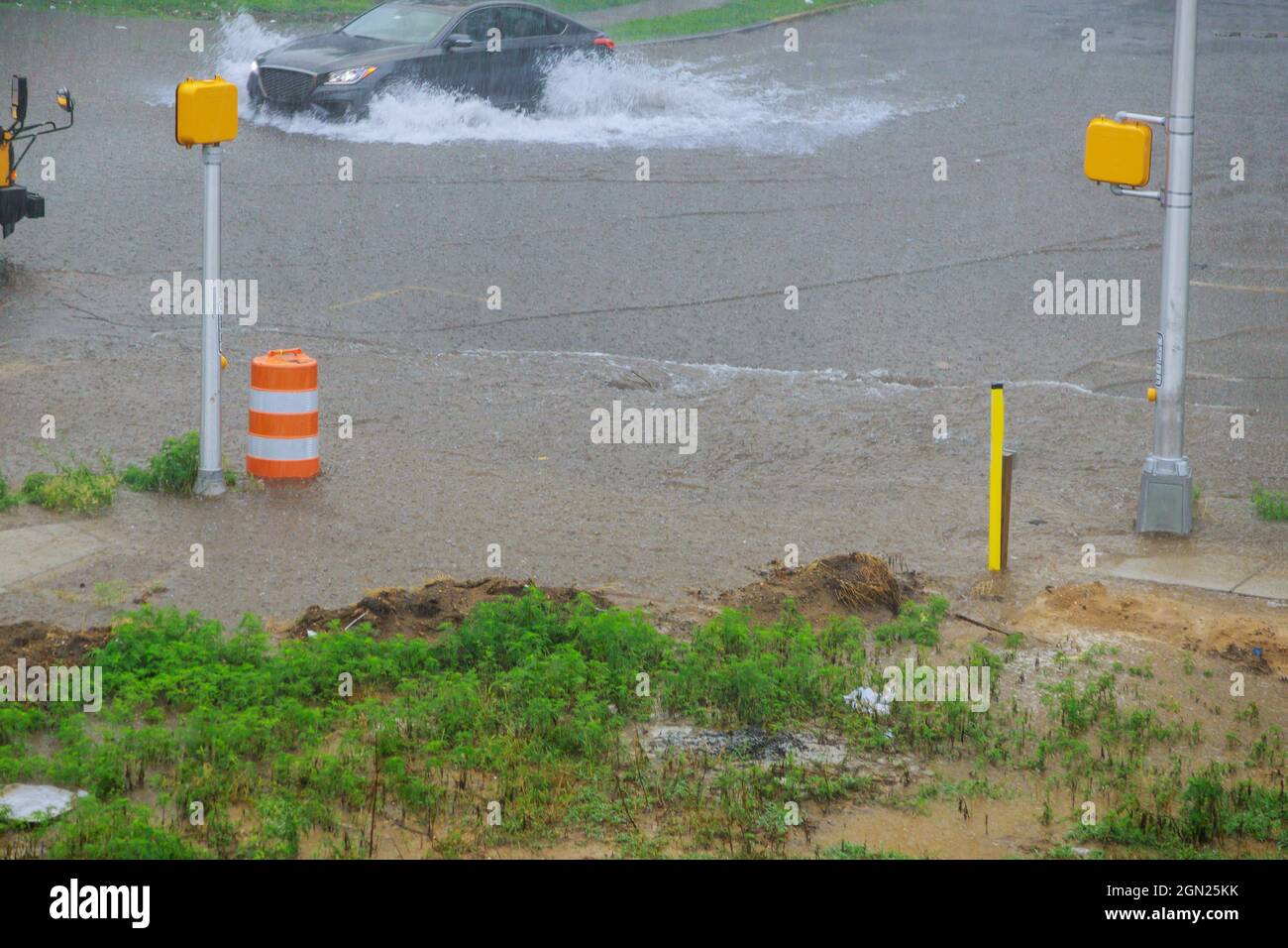 A car going fast through a large puddle flooding the road during a ...