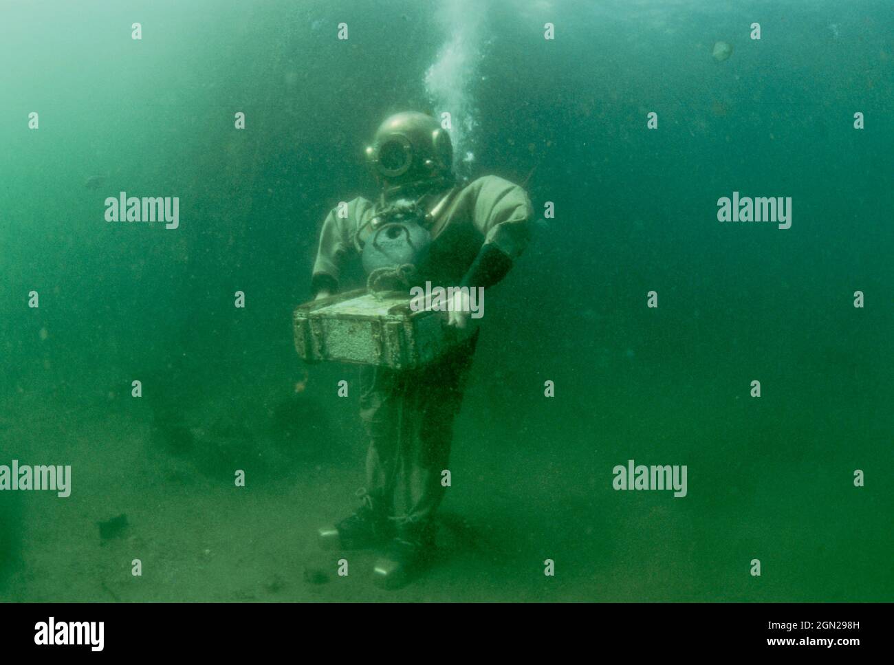 Hard-hat or ’standard dress’ diver with ammunitions box. He is from the ...