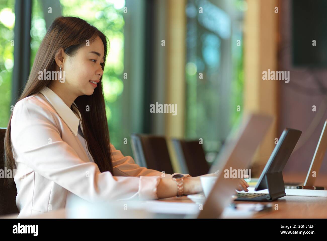 Young female assistant working and typing on tablet keyboard in ...