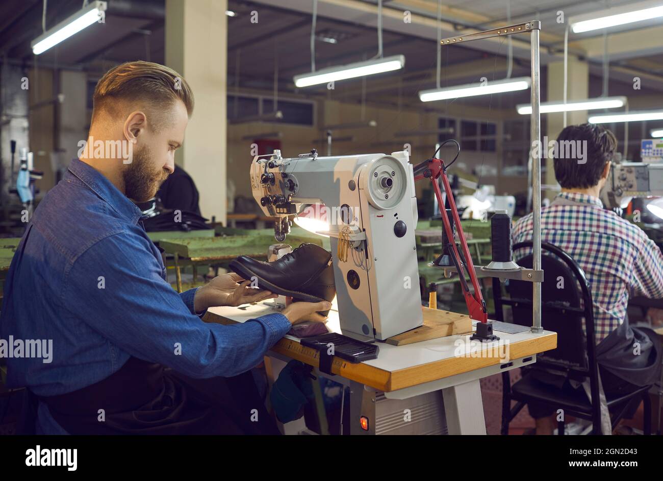 Craftsman shoe designer sewing boot on stitching machine side view shot ...
