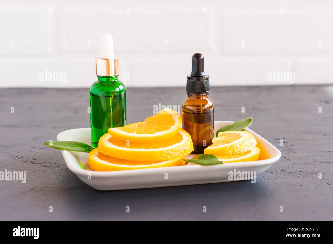 facial serum in glass bottles with pipette, orange slices, green leaves ...