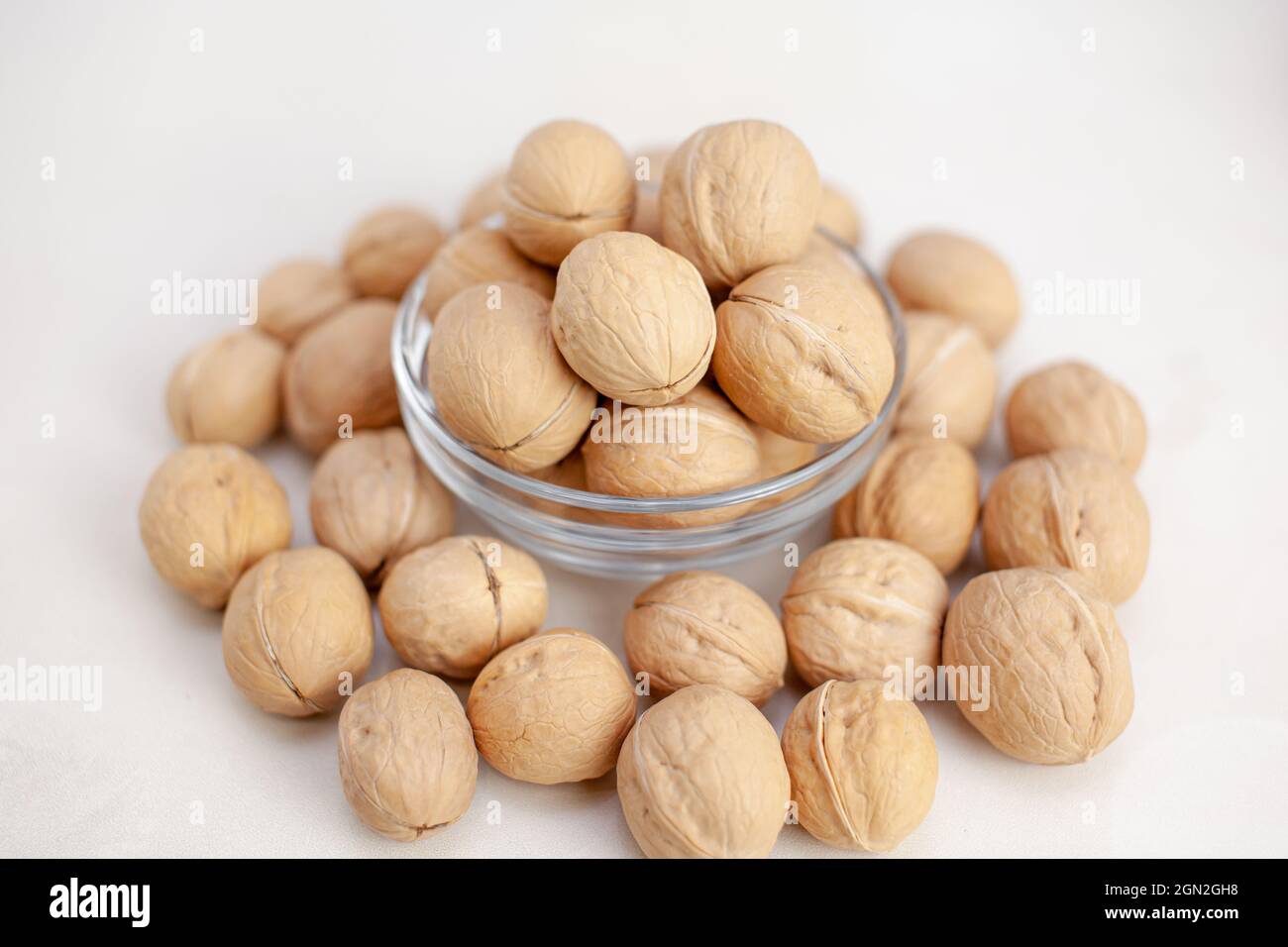 A lot of whole walnuts in a cup on a white background. Healthy food ...