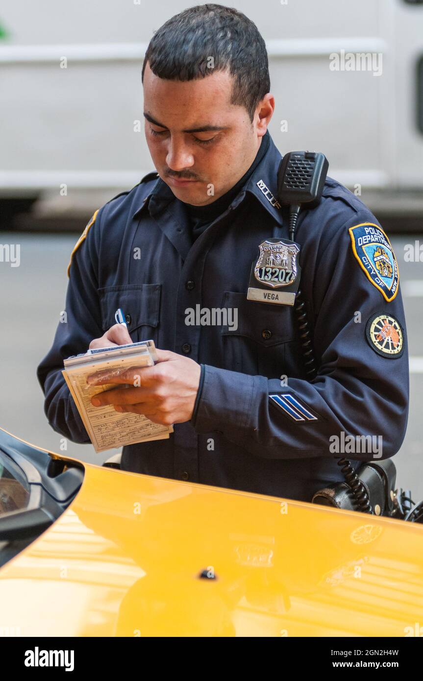 UNITED STATES, NEW YORK, MANHATTAN, A POLICE OFFICER WRITING A TICKET ...
