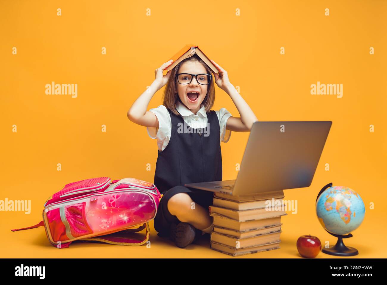 Emotional pupil sits behind a stack of books and laptop holds book on ...