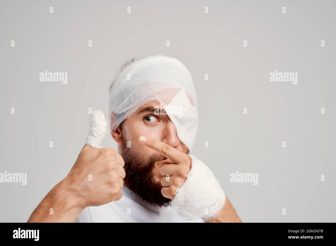 bearded man with bandaged head and eye hospitalization light background ...