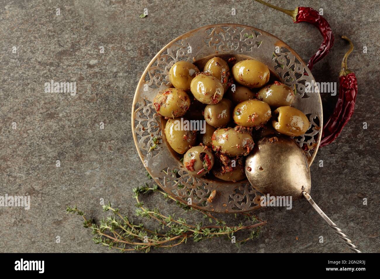 Spicy green olives in olive oil on a old stone table. Top view Stock ...
