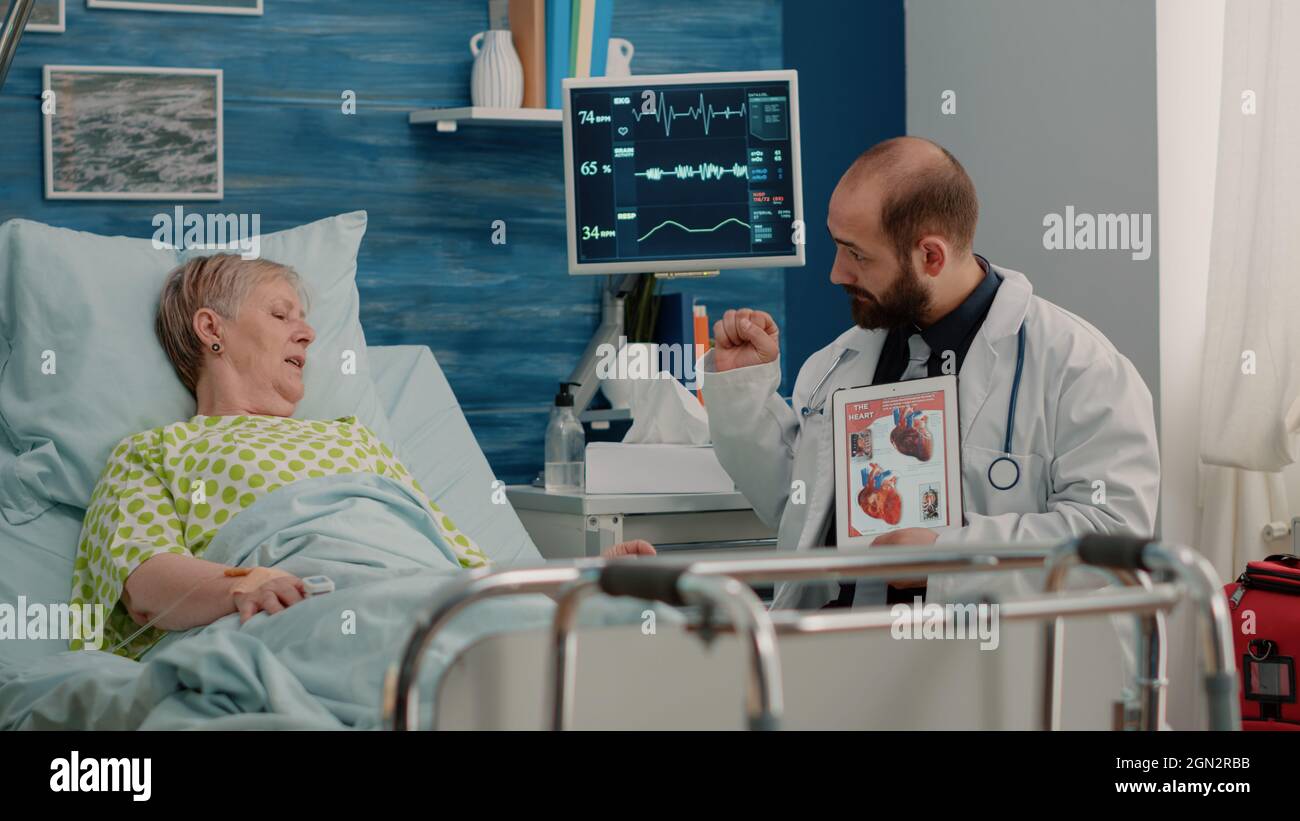 Doctor showing cardiovascular image on tablet to ill patient in ...