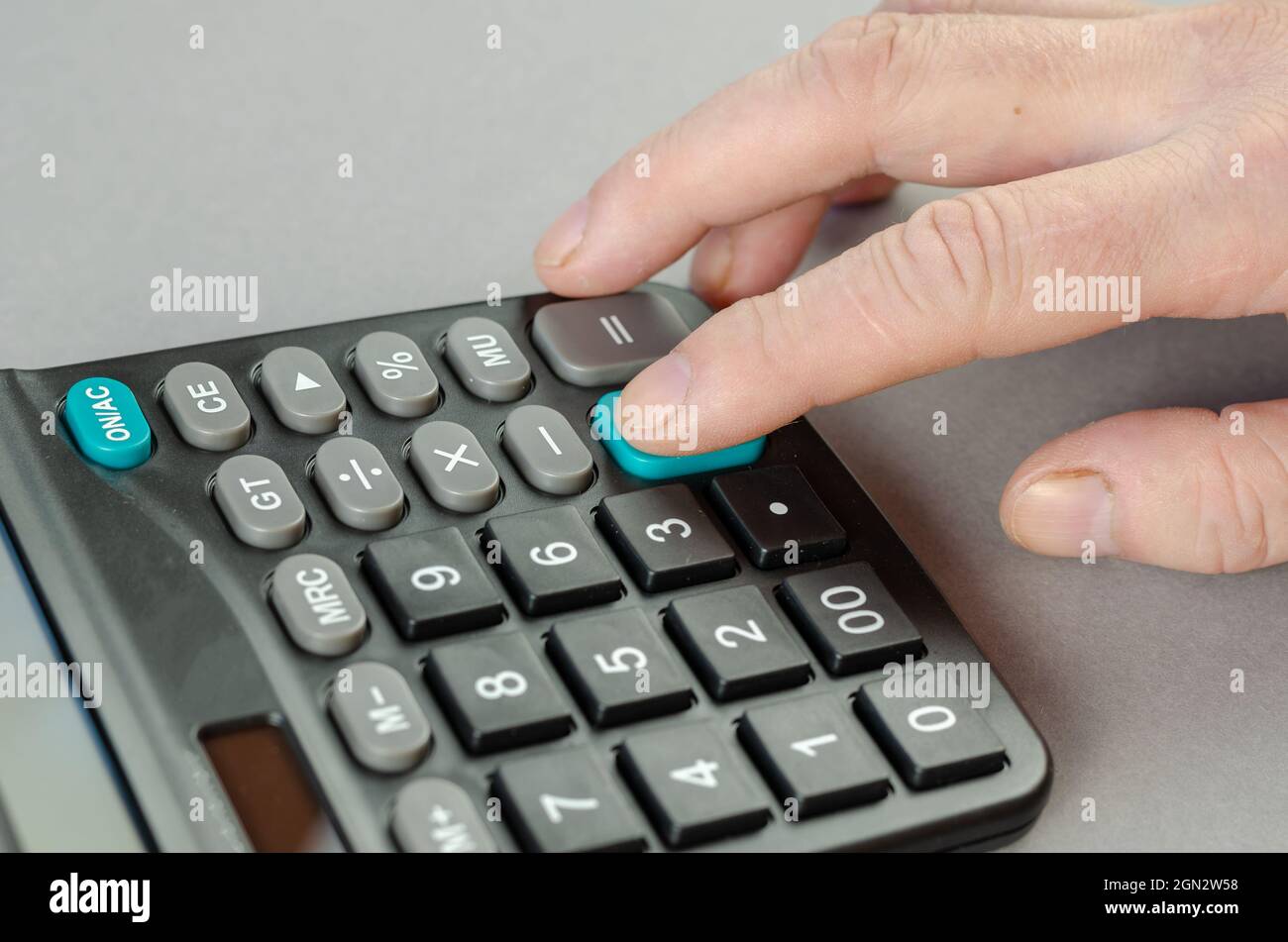 The man's index finger presses the green plus key of the calcula Stock ...