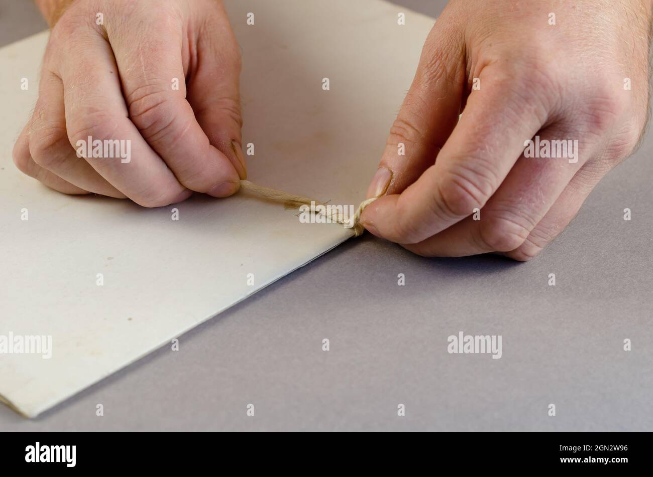 Two hands tie a knot on a document folder. Paper folder on gray Stock ...