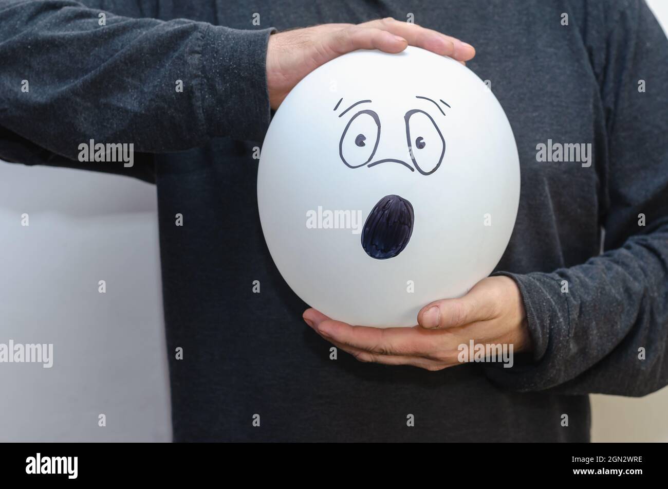 Man holding balloon with face drawn in front of him. White ballo Stock ...