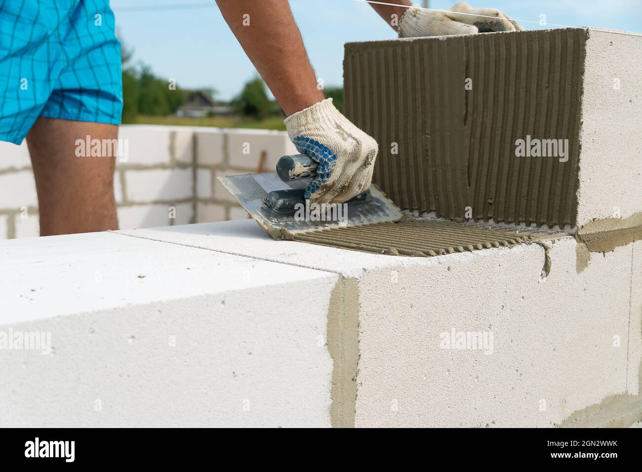 Builder uses a notched trowel to apply the cement mixture to the sides ...