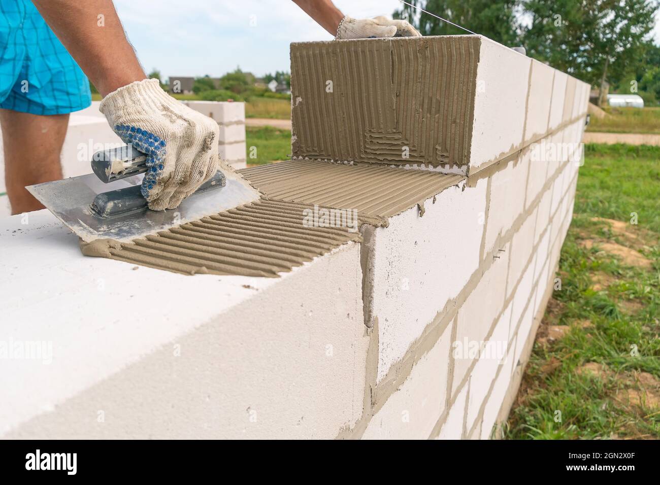 Builder uses a notched trowel to apply the cement mixture to the ...
