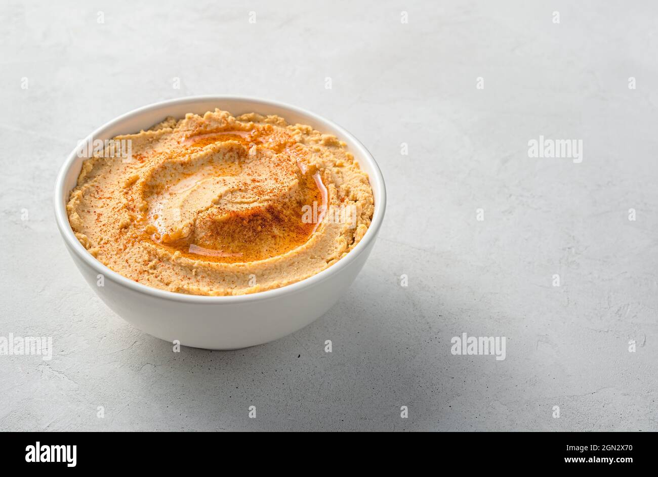 Traditional hummus with sesame seeds, paprika and olive oil on a gray ...