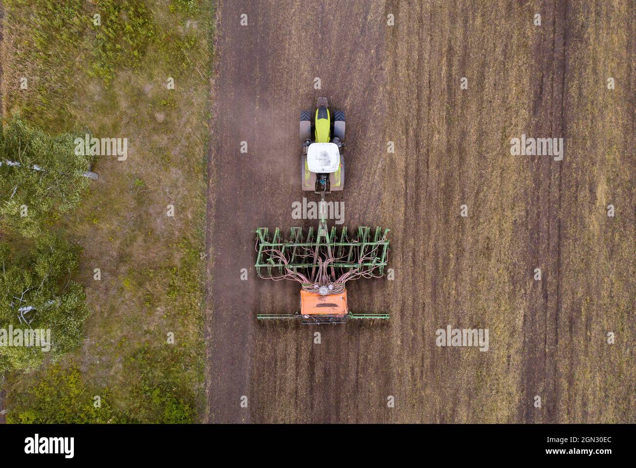Aerial view of agricultural tractor with seeder machine at work on the ...