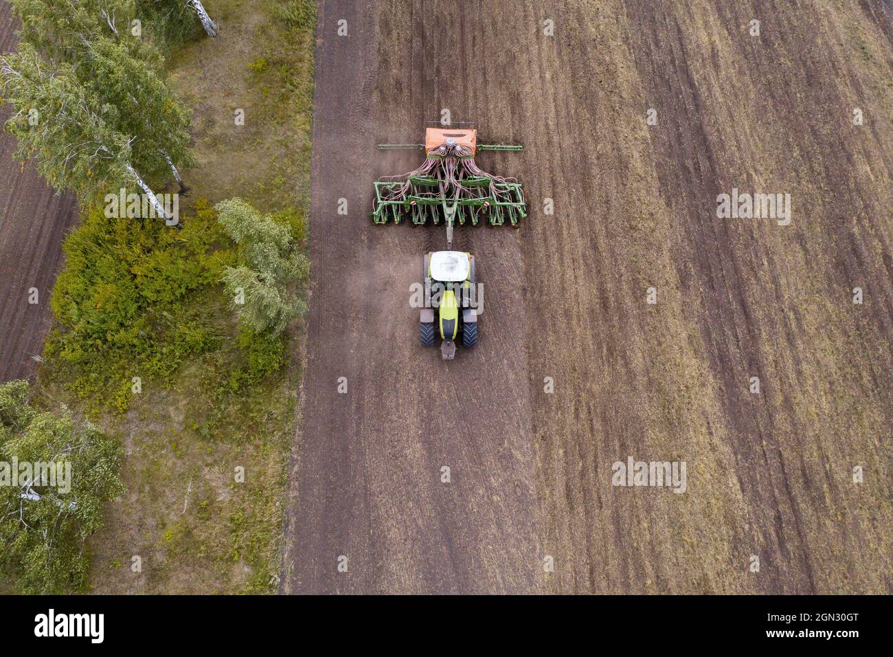 Aerial view of agricultural tractor with seeder machine at work on the ...