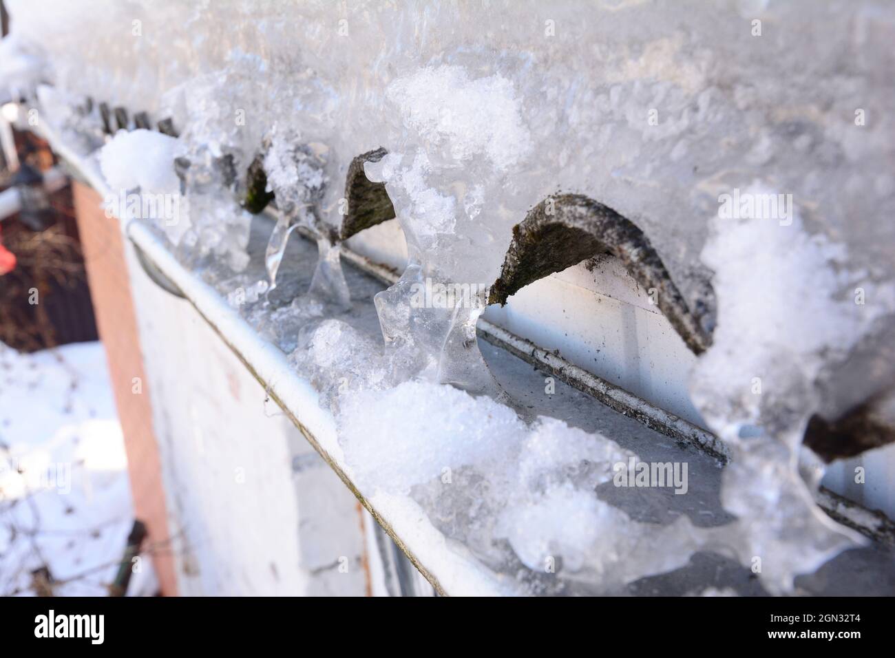 Rain gutter full of ice in winter. Frozen ice in house roof gutter ...
