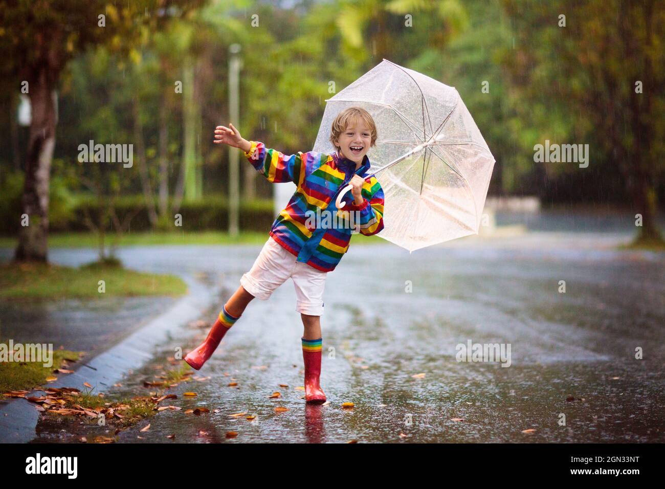 Child playing in autumn rain. Kid with umbrella. Little boy running on ...