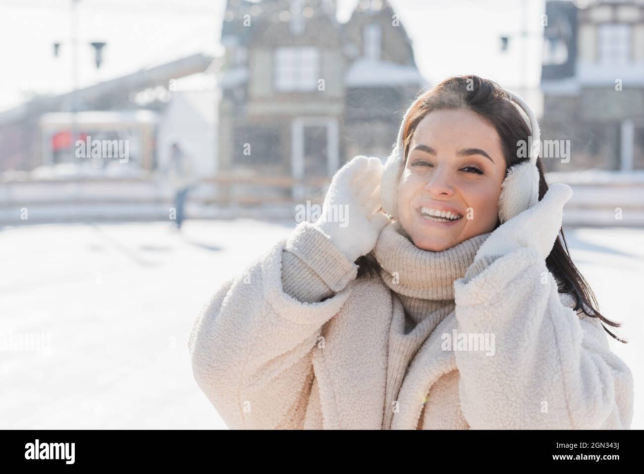 happy young woman adjusting ear muffs outside Stock Photo - Alamy