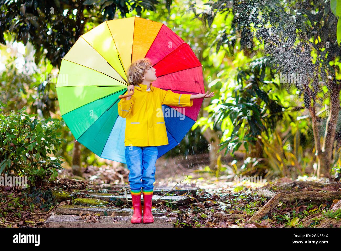 Child playing in autumn rain. Kid with umbrella. Little boy running in ...