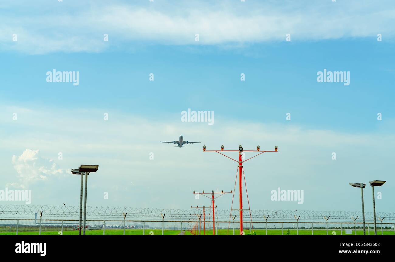 Commercial airplane flying above approach light at the airport ...