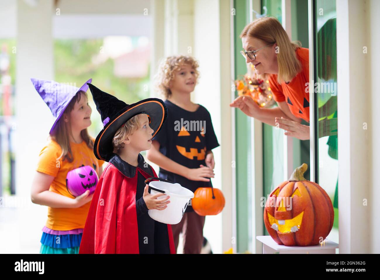 Kids trick or treat on Halloween night. Child at decorated house door ...